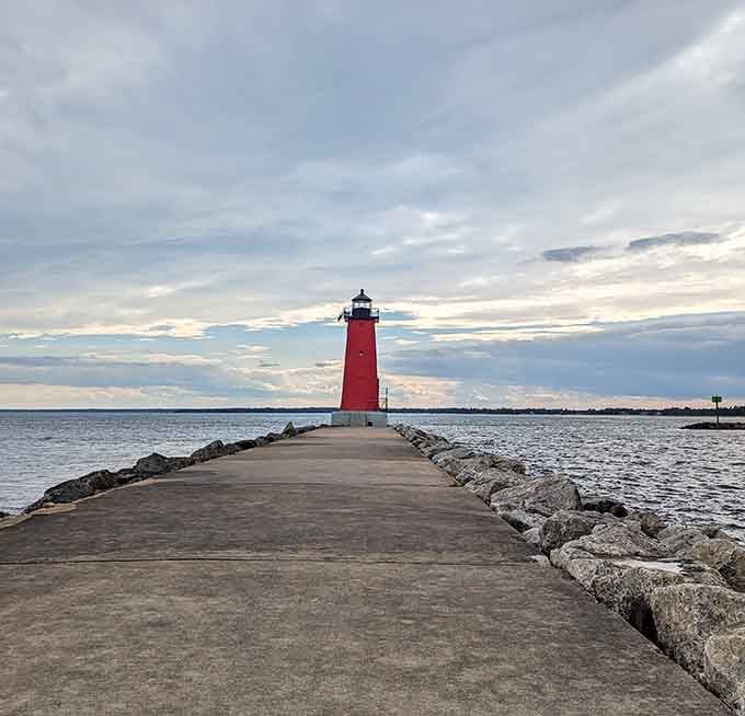 The red lighthouse stands sentinel at pier's end, a beacon that's been guiding ships home for generations.