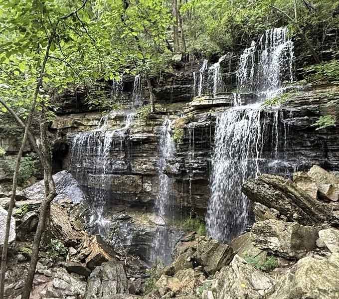 Multiple delicate streams dance down layered rock faces like synchronized swimmers performing their greatest hits.