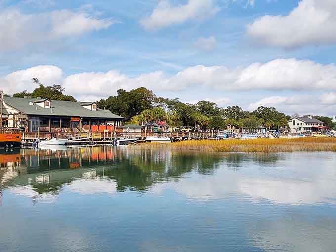 Golden hour light bathes the waterfront where marsh grass sways and boats bob gently at their moorings.