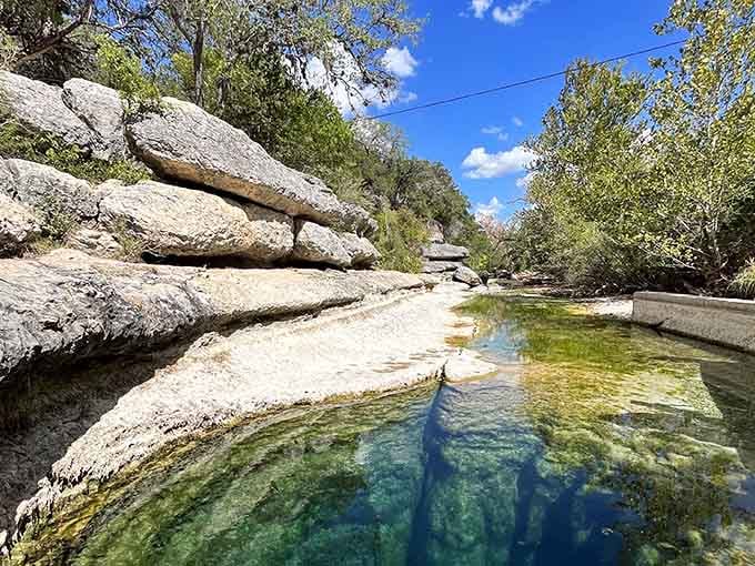 Crystal-clear water reveals the mysterious depths below, where limestone walls descend into an underground cave system.