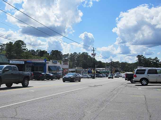 Everyday traffic flows past homes where porches still mean something and mortgage payments don't require winning the lottery.