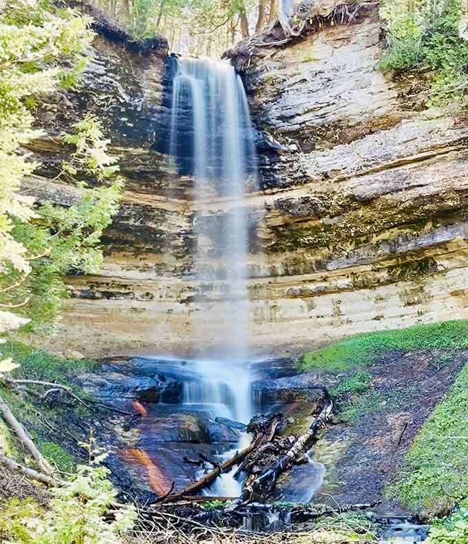 A delicate ribbon of water drops down layered sandstone like silk sliding off a table in slow motion.