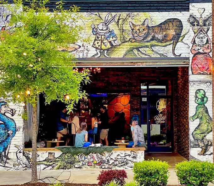 Whimsical murals featuring the White Rabbit and Cheshire Cat transform this storefront into pure storybook enchantment for diners.