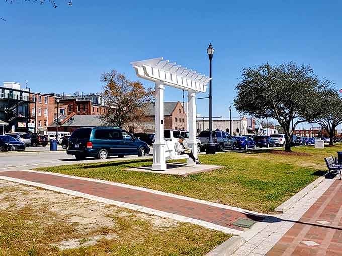 That white pergola stands like a welcoming gateway to waterfront relaxation and unhurried afternoon strolls.
