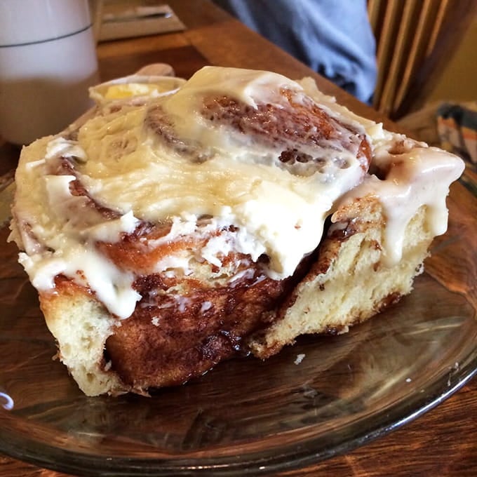 Behold the cinnamon roll that launched a thousand road trips, dripping with cream cheese frosting like edible architecture.
