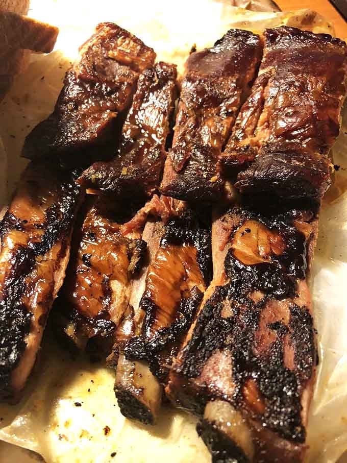 These ribs showcase that perfect smoke ring and glistening glaze that makes grown adults forget their table manners completely.