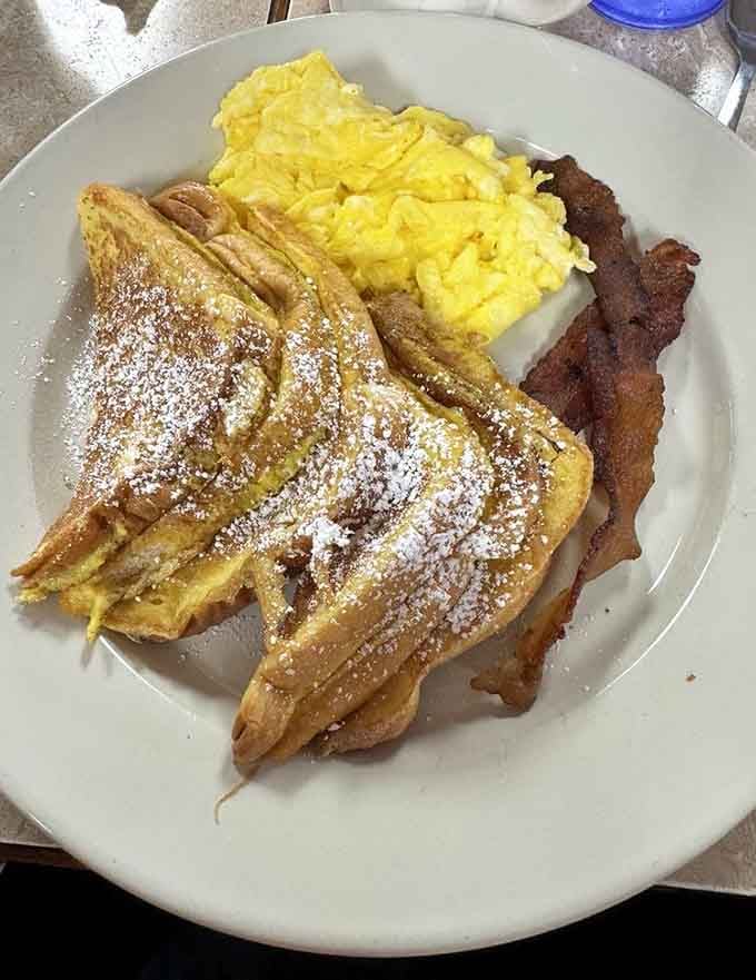 French toast dusted with powdered sugar, scrambled eggs, and bacon: the holy trinity of morning happiness.