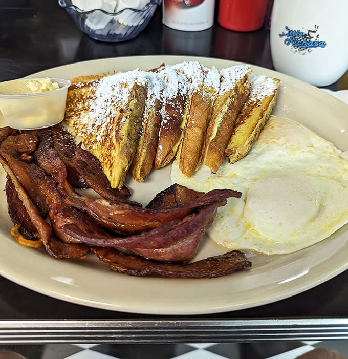 French toast dusted with powdered sugar, eggs sunny-side up, and bacon cooked to that perfect crispy-chewy sweet spot.