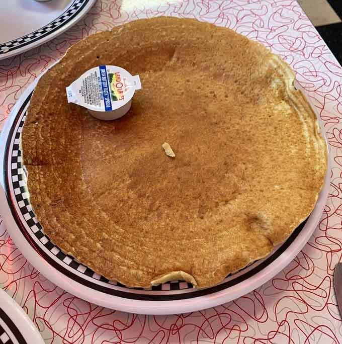 That pancake is so massive it makes the butter container look like it's visiting from Lilliput's breakfast table.