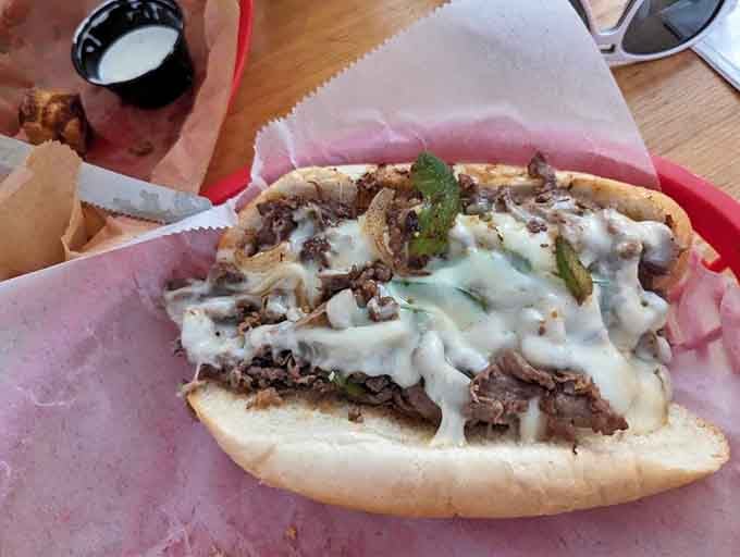 That glorious cheese cascade over perfectly grilled meat is what happens when Wisconsin meets Philadelphia in the best way.