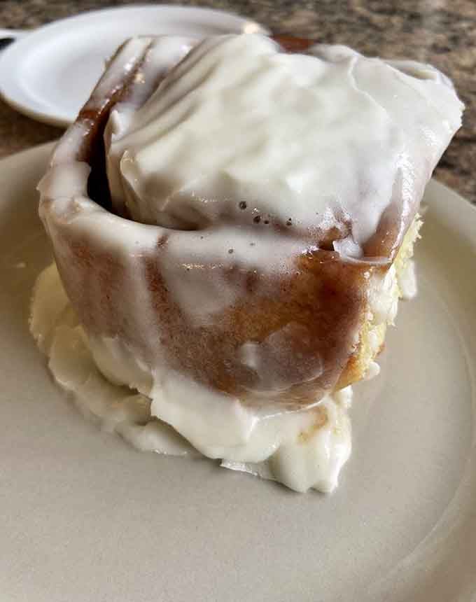 Behold the crown jewel: a cinnamon roll so magnificent it deserves its own ZIP code. Frosting applied with admirable generosity.