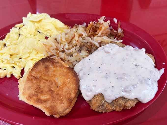 Country fried steak with gravy that could make a vegetarian reconsider their life choices, served on appropriately cheerful red plates.