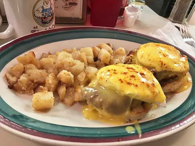 Behold the star attraction: Eggs Benedict with hollandaise cascading like a golden waterfall over perfectly poached eggs. This is breakfast architecture at its finest.