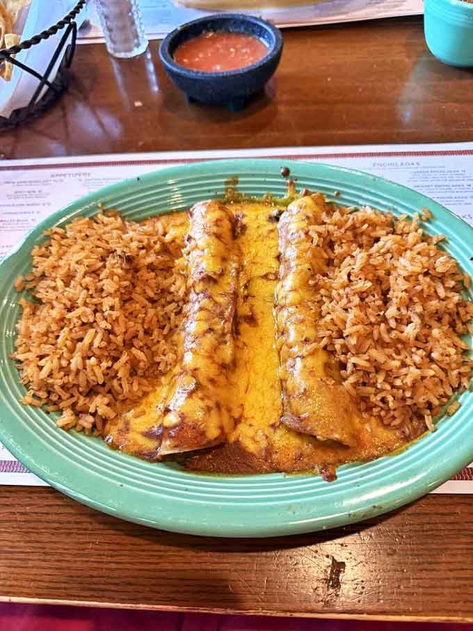 Cheese enchiladas swimming in chili con carne with Mexican rice on the side&mdash;this isn't just dinner, it's therapy on a turquoise plate.