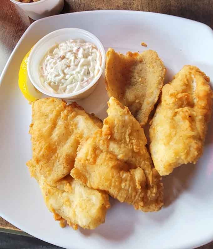 Golden-battered perfection arrives with coleslaw and lemon, proving why people drive from counties away for this legendary fish fry experience.