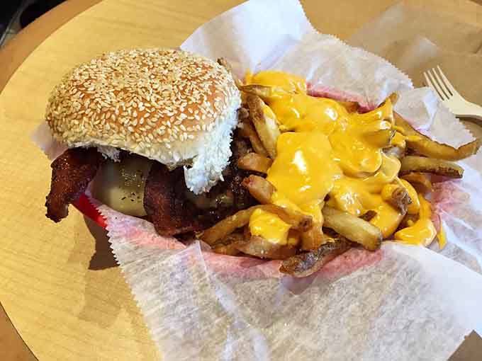 Behold the sesame seed bun, the bacon, the pickles, and those cheese-covered fries plotting to ruin your diet in the best possible way.