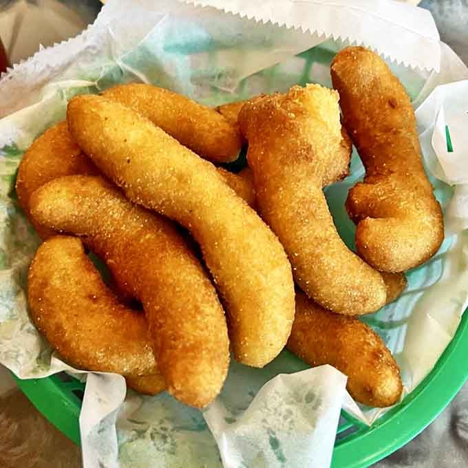 Golden-brown hush puppies that crackle when you bite them, then surrender to a pillowy interior. Worth the drive from anywhere with a gas station.