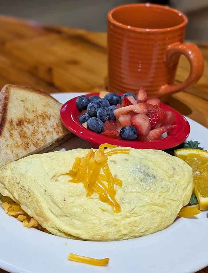 That fluffy omelet with melted cheese cascading down the side is basically morning perfection on a plate.