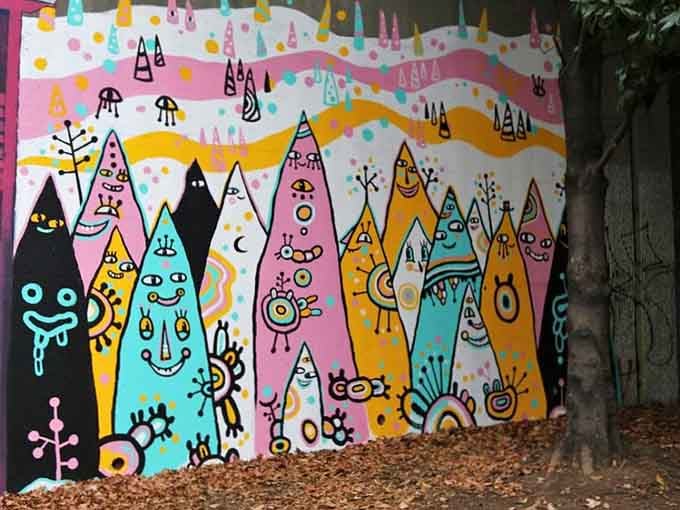 Whimsical triangular beings march across this fence like a psychedelic mountain range designed by someone's delightfully weird imagination.