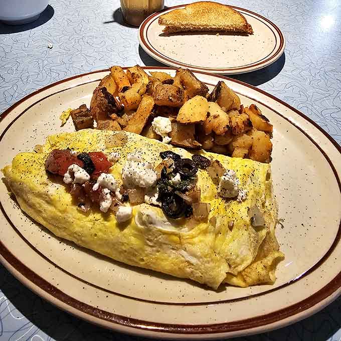 That omelet is stuffed with feta, tomatoes, and olives, proving the Greeks knew their way around breakfast perfection.
