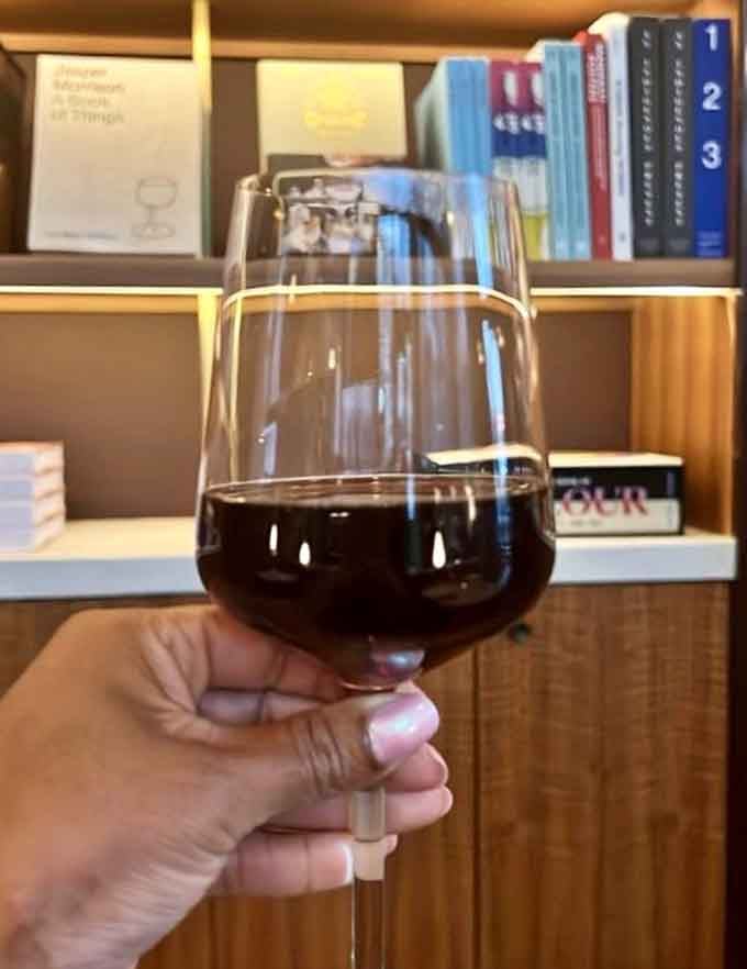A glass of Sangiovese positioned perfectly against literary classics, because some pairings just make sense in this world.