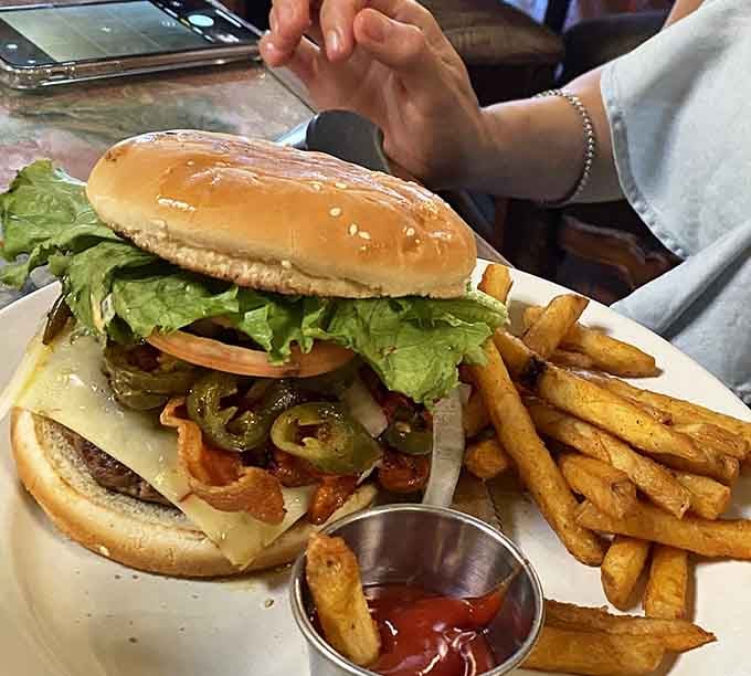 This burger towers like it's trying to reach the second floor, complete with jalapeños and enough cheese to reconsider your life choices.