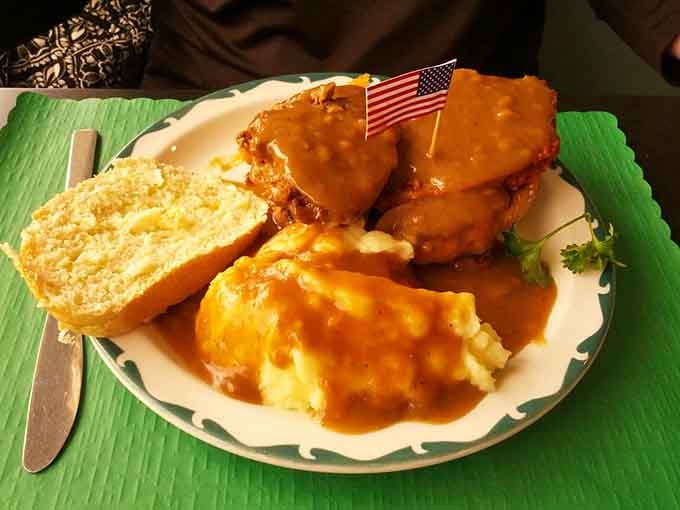Two thick slices of legendary meatloaf swimming in gravy, flanked by mashed potatoes that understand their assignment perfectly.