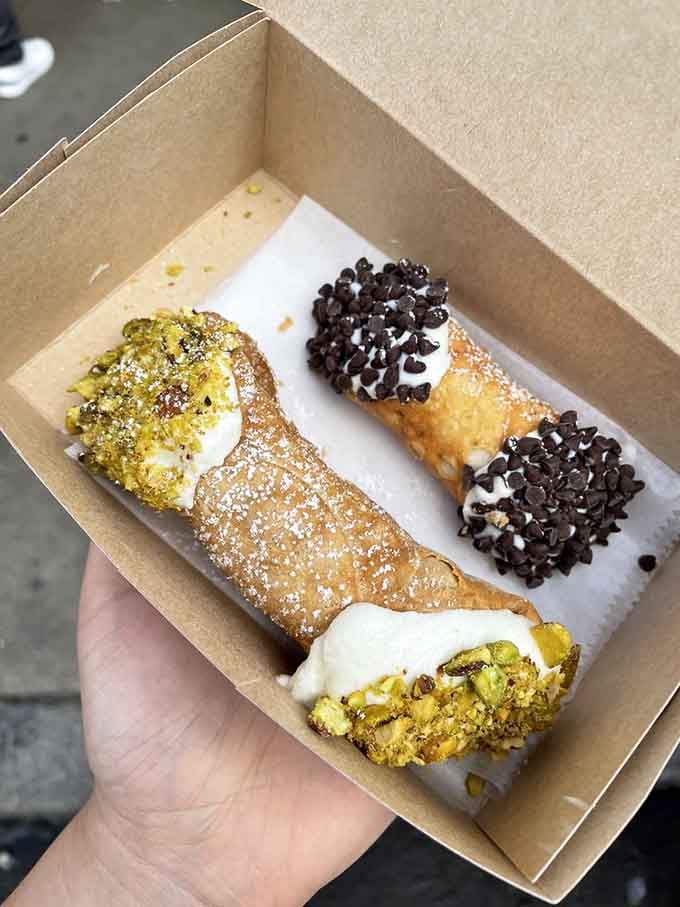 Freshly filled cannoli with pistachios and chocolate chips, proving that sometimes life's best decisions come in crispy shells.