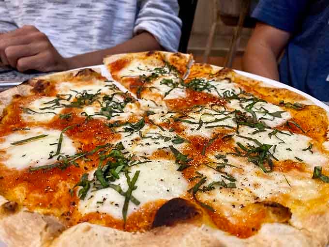 The Margherita pizza showcases perfectly charred crust, fresh basil, and those beautiful leopard spots that signal wood-fired perfection.