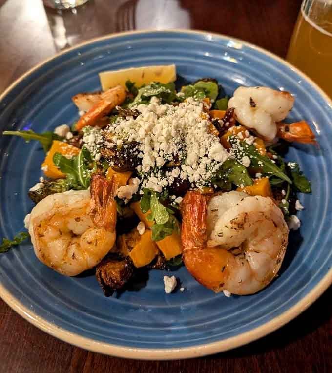 Jerk shrimp nestled among roasted vegetables and greens, proving that pub food can be both vibrant and sophisticated.