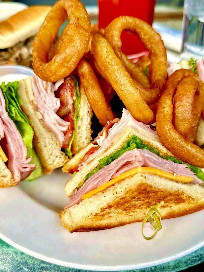 This towering club sandwich with golden onion rings proves that sometimes the classics need no mysterious twist.