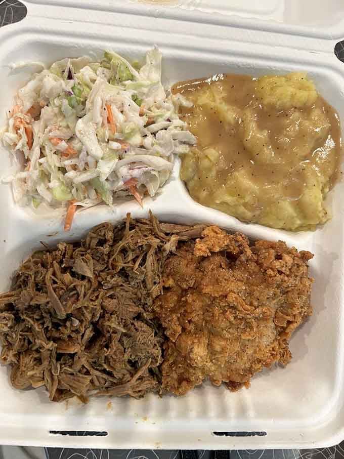 Pulled pork and fried chicken share a plate with coleslaw and mashed potatoes in perfect harmony.
