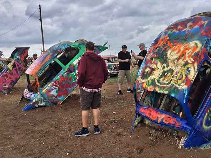 Visitors contemplating their artistic masterpiece like they're about to paint the Sistine Chapel, except it's a Beetle and way more fun.