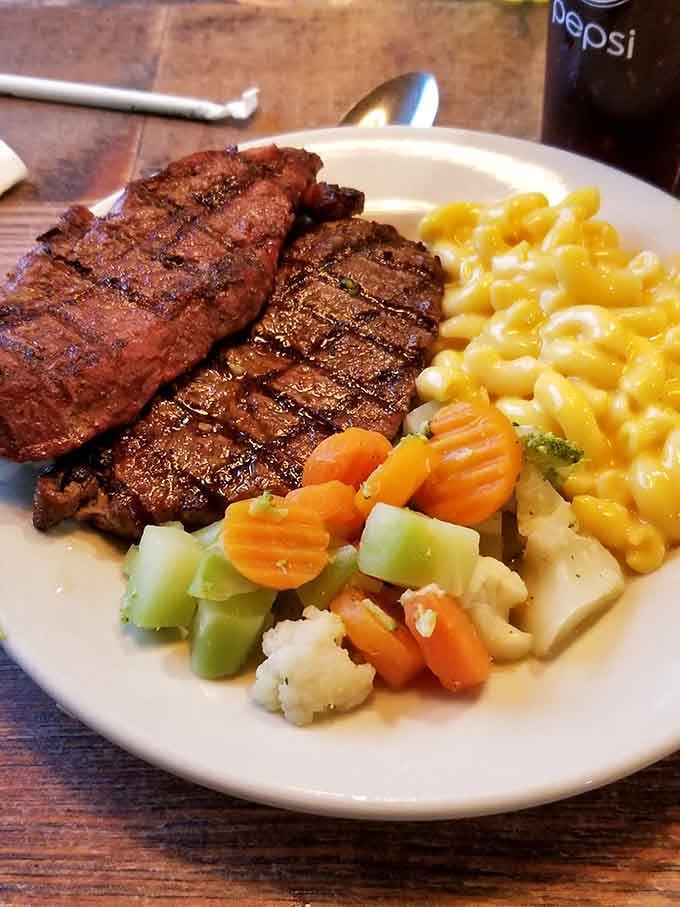 Perfectly grilled steak sits alongside mac and cheese and vegetables, proving that buffets can absolutely deliver quality over quantity.