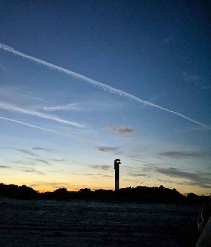 As twilight paints the sky, the lighthouse beacon begins its nightly vigil, silhouetted against nature's own spectacular light show.