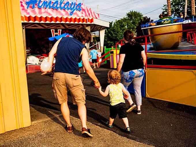 Family moments in the making: Parents and child navigate the midway hand-in-hand, creating memories that will outlast any souvenir.
