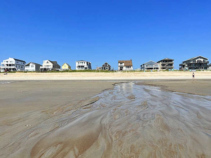 Beach houses stand like sentinels along the shoreline, their weathered charm a testament to generations of summer memories made with sand between toes.