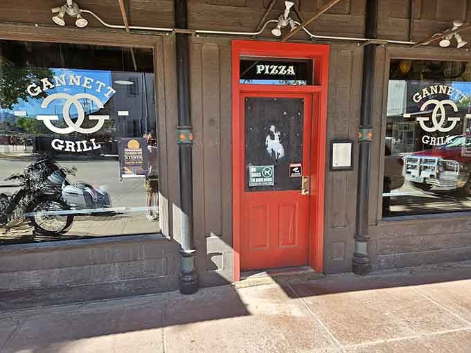 The iconic red door of Gannett Grill beckons hungry travelers like a culinary lighthouse in downtown Lander.
