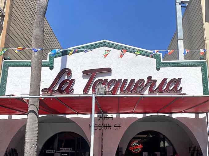 Colorful flags flutter above this Mission District landmark, where burrito dreams come true beneath that famous red sign.