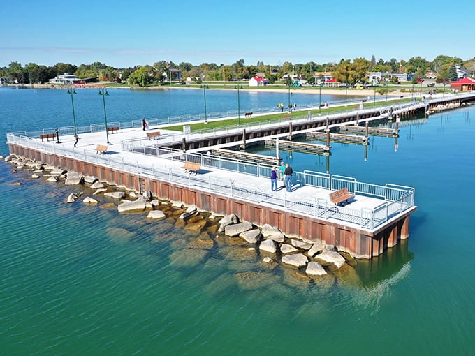 Turquoise waters lap against modern piers where anglers cast lines and dreamers watch clouds drift across Tawas Bay.