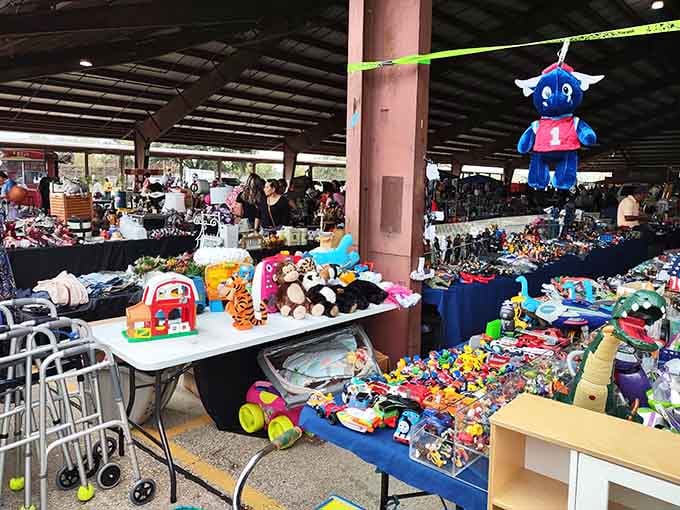 That cheerful blue mascot hanging overhead adds whimsy to a marketplace bursting with toys and childhood memories come alive.