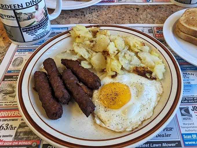 Sausage links, perfectly fried eggs, and golden hash browns form the holy trinity of morning sustenance on one plate.