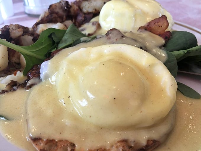 Hollandaise sauce cascading over perfectly poached eggs like a golden waterfall of pure breakfast happiness and butter-based joy.