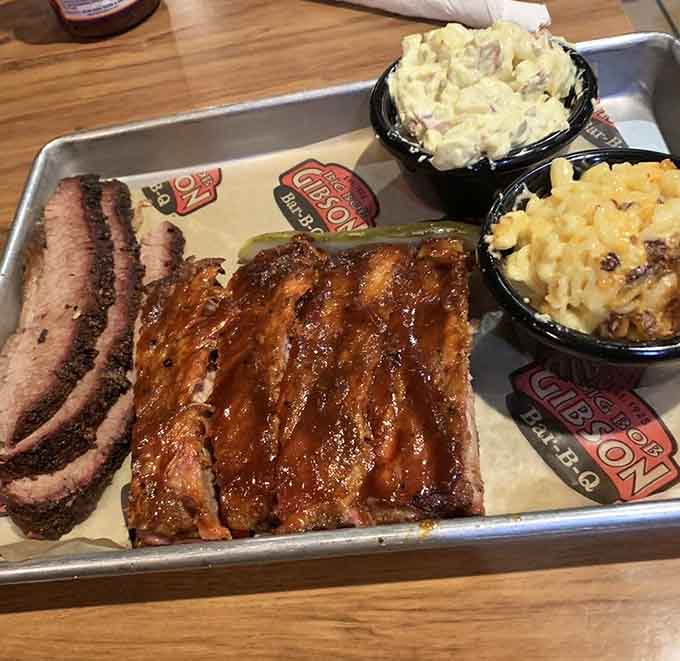 This tray showcases championship-level barbecue: tender brisket, glazed ribs, creamy sides, and those iconic Big Bob Gibson stickers of honor.