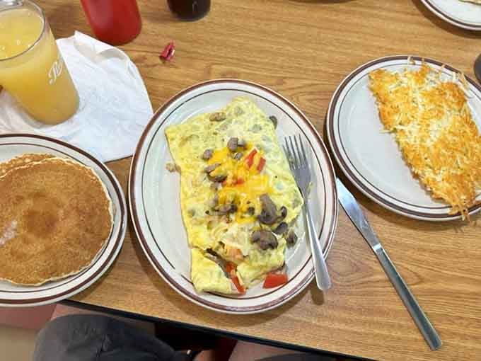 That omelet is stuffed with vegetables and cheese, looking like it just won the lottery of breakfast ingredients.