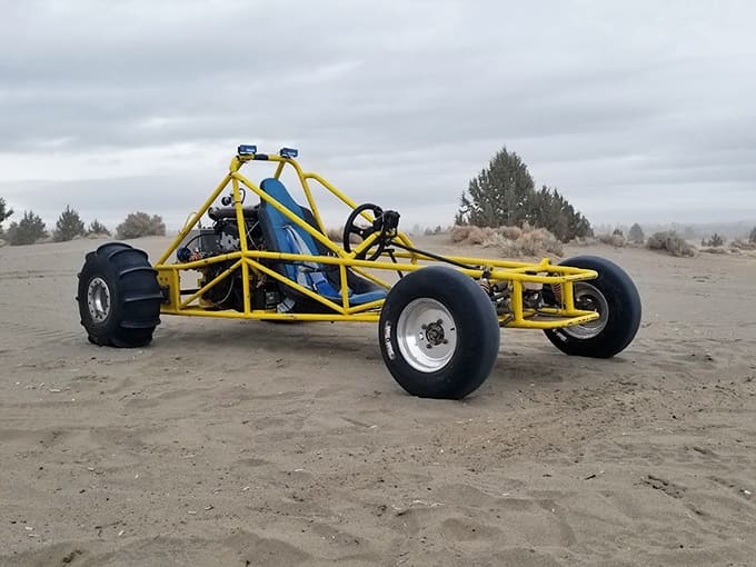 A bright yellow dune buggy sits ready for action on the sand, built for speed and desert thrills.
