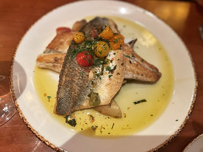 Fresh branzino swimming in herbs and cherry tomatoes, because even fish deserve a Mediterranean vacation on your plate.