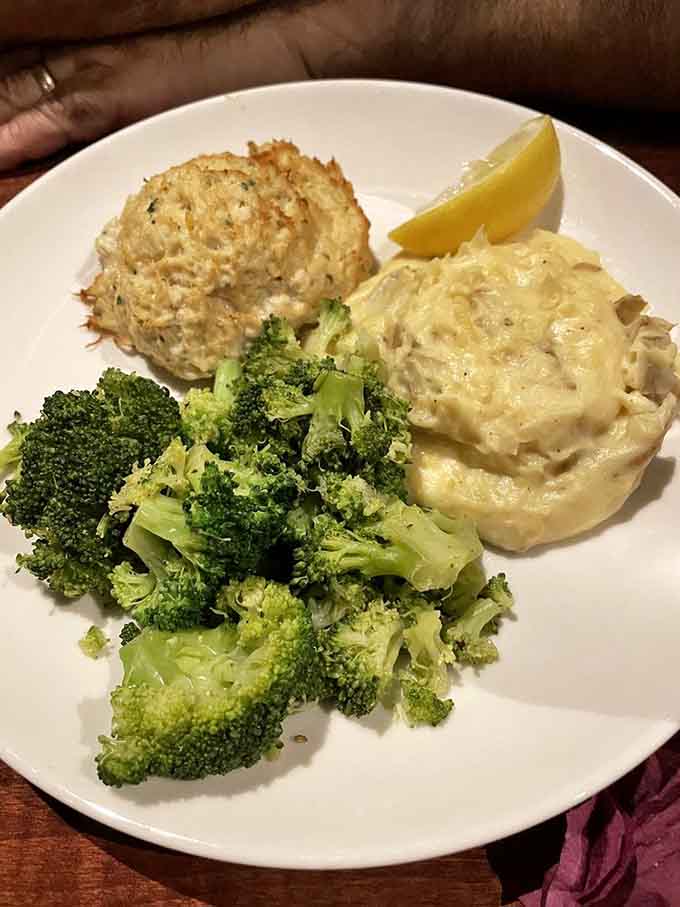The crab cake arrives like a golden crown atop creamy potatoes, with broccoli playing the role of "yes, this is technically a balanced meal."