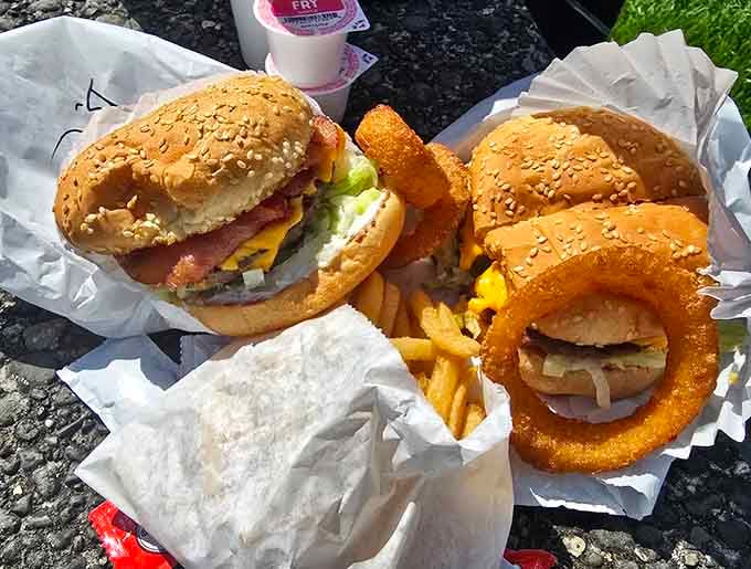 Golden sesame buns, crispy onion rings, and fries create the holy trinity of drive-in perfection on one table.
