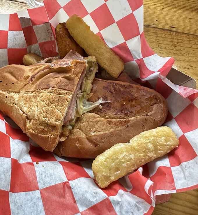 The Cuban sandwich arrives like a pressed masterpiece, with golden tostones standing guard like delicious sentries.